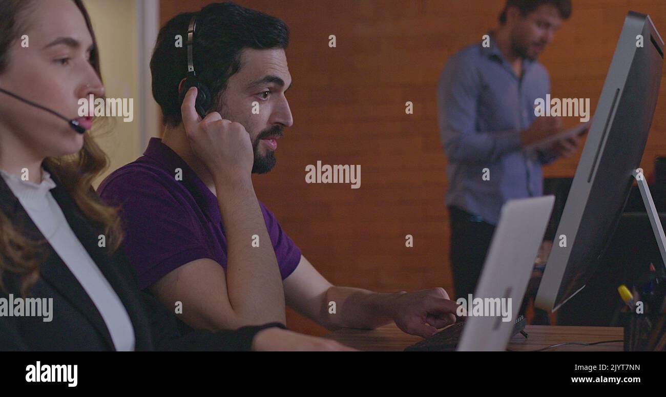 Telemarketers communicating with clients wearing headsets in front of ...