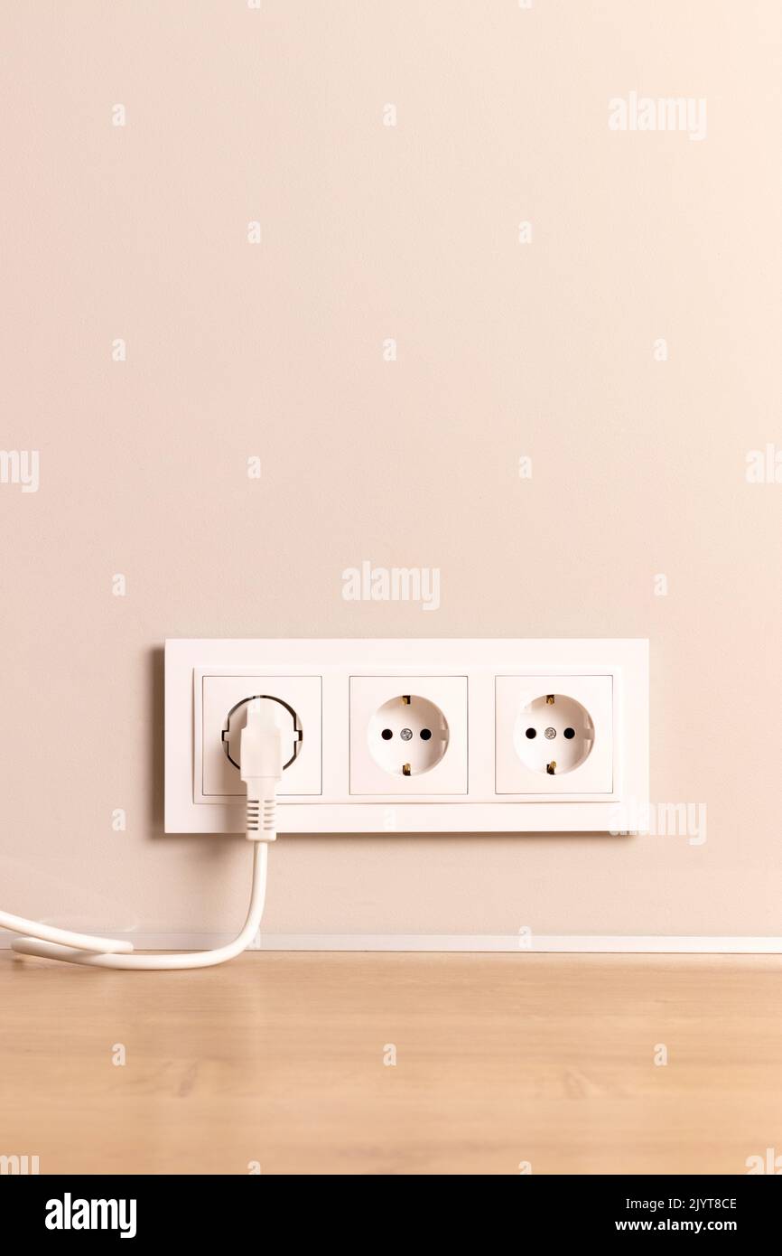 Group of white european electrical outlets with plug inserted into it ...