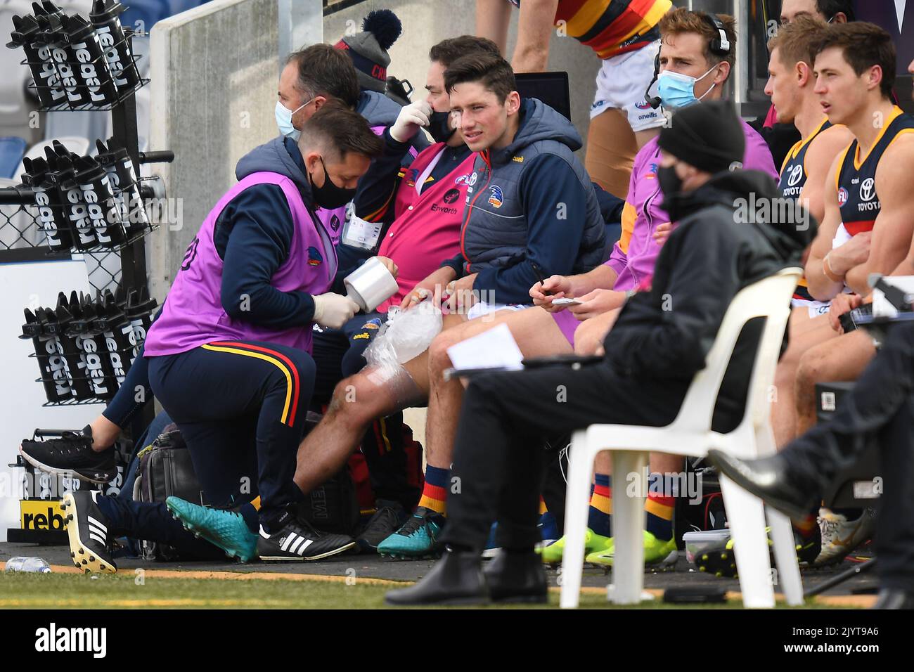 Chayce Jones (centre) of the Adelaide Crows is attended to by medical ...