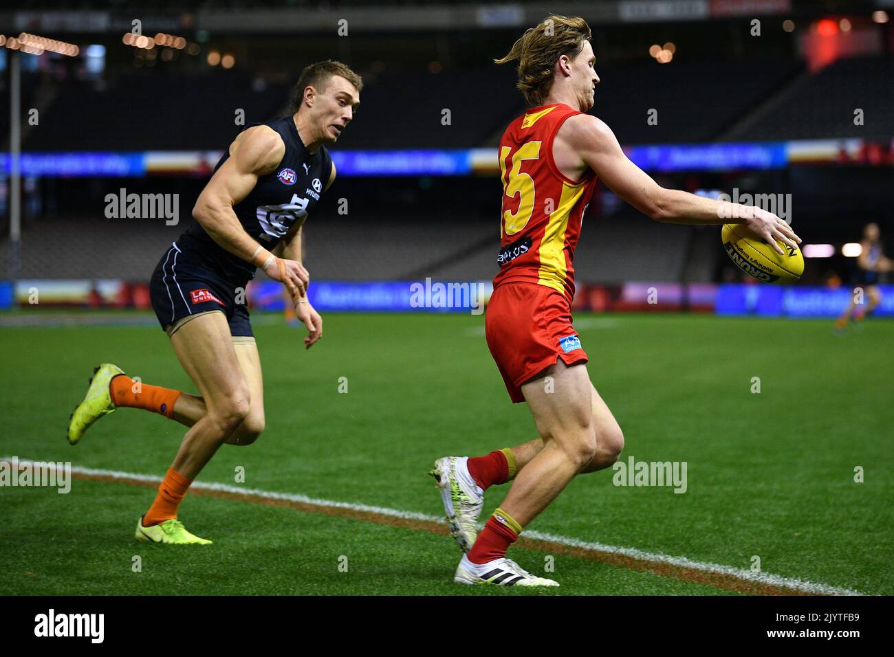 Noah Anderson of the Suns (right) kicks the footy during the AFL Round ...