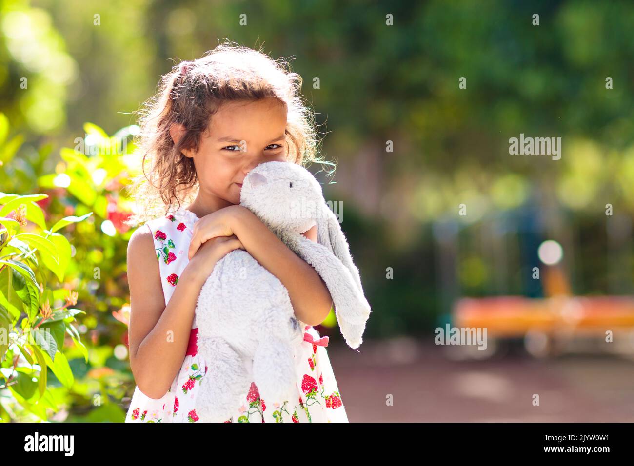 Kids on playground. Little cute curly girl with toy bunny. Children ...