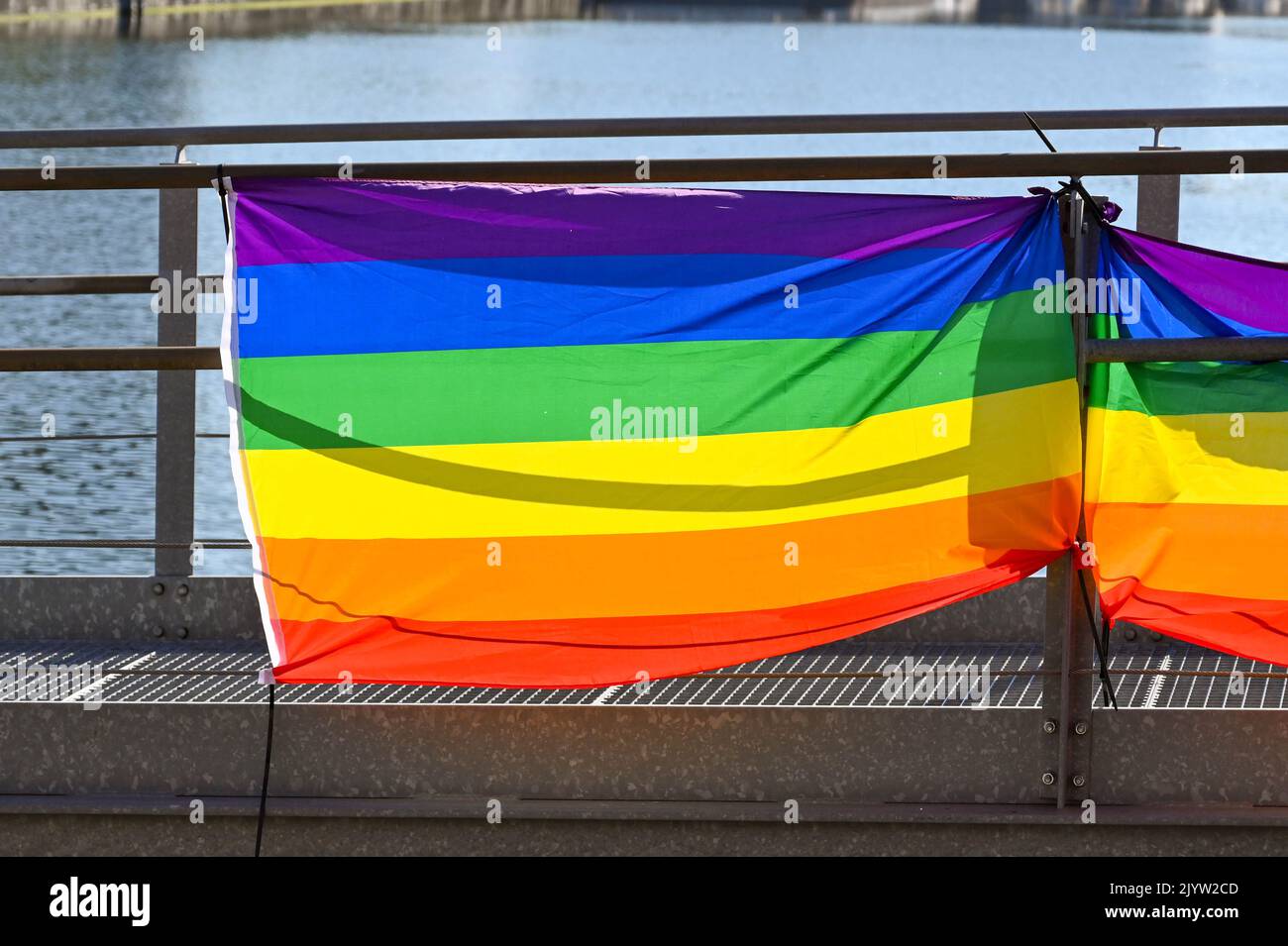 Flag in Pride rainbow colours tied to metal railings in a city for a ...