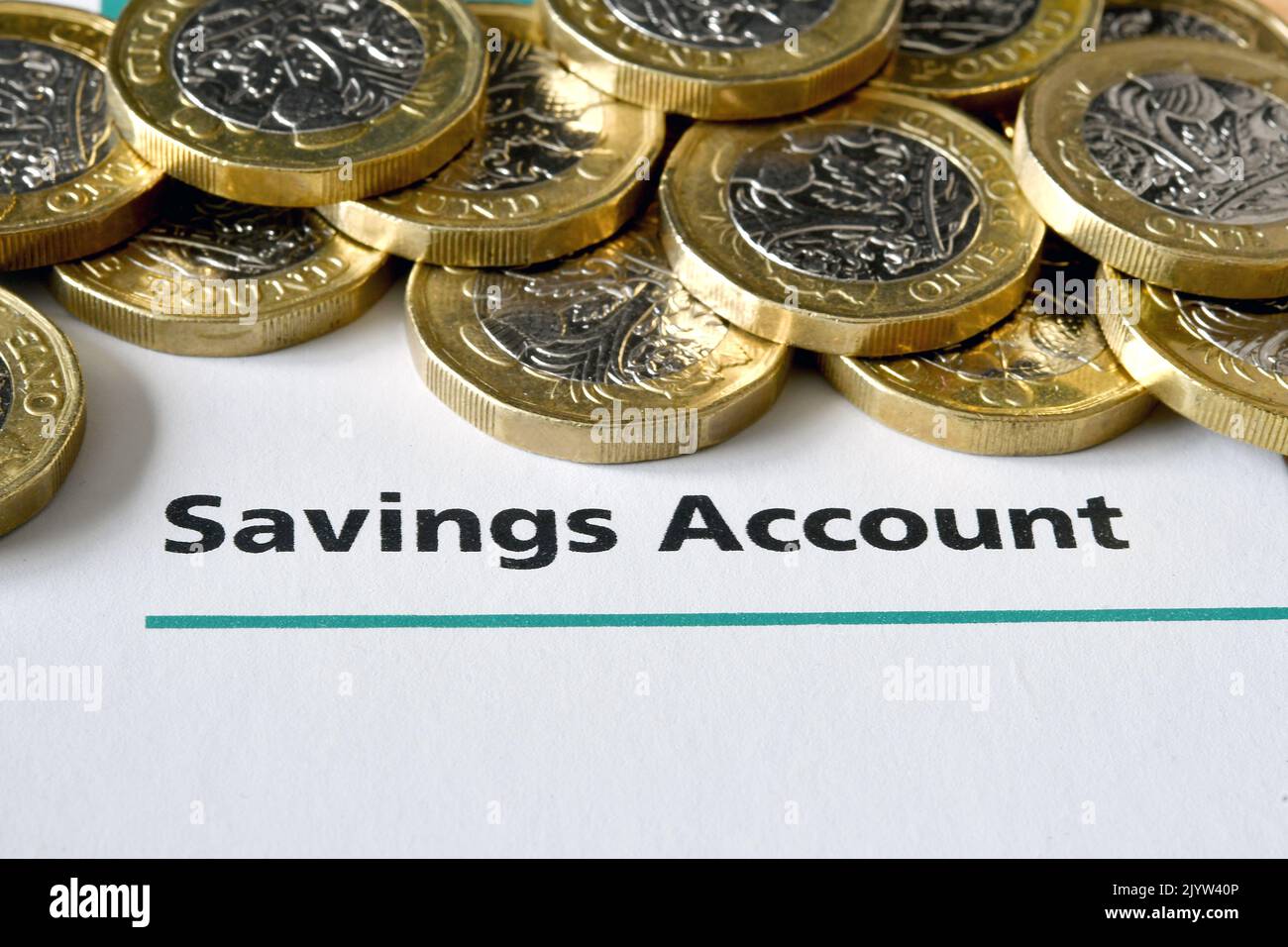 British one pound coins on top of the cover of a savings book. No ...