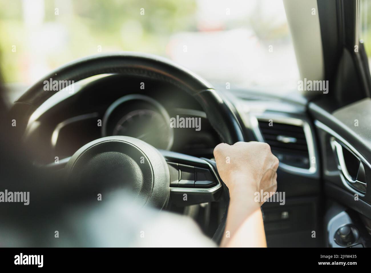 Close up of woman driving hand holding steering wheel in blur ...