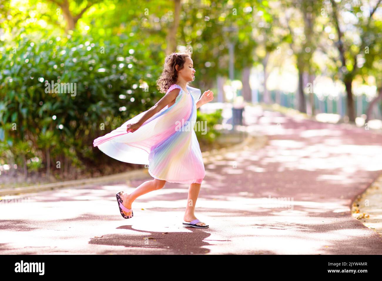 Happy kid playing in summer park. Little girl dancing in beautiful ...