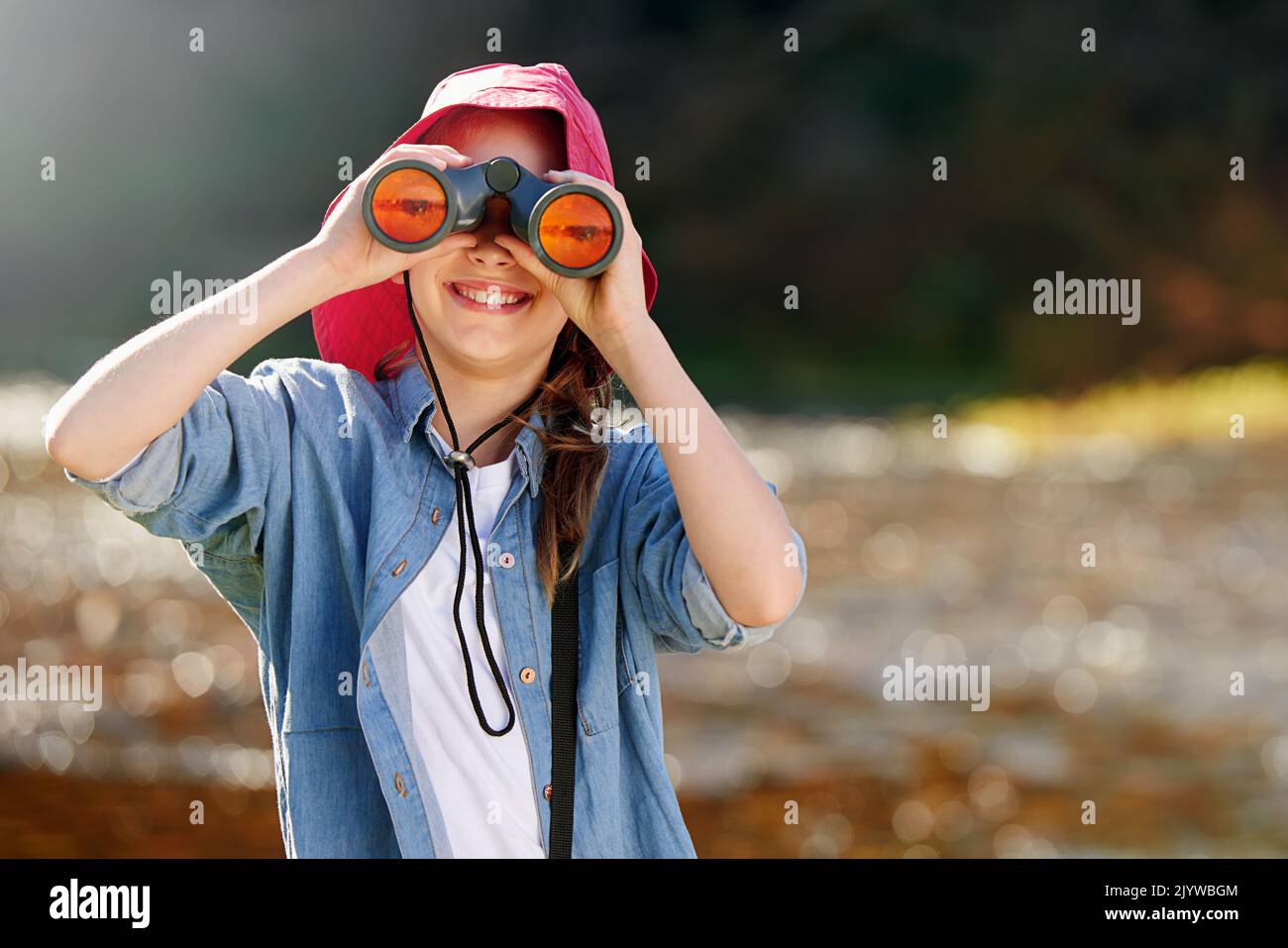 So much to see. A young girl looking through binoculars in the outdoors ...