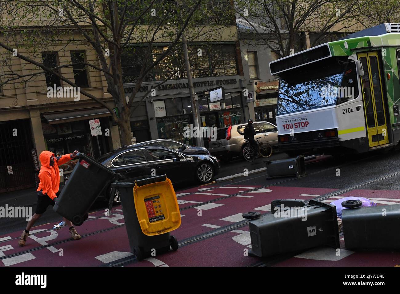 A construction worker throws garbage bins at a tram at a protest at ...