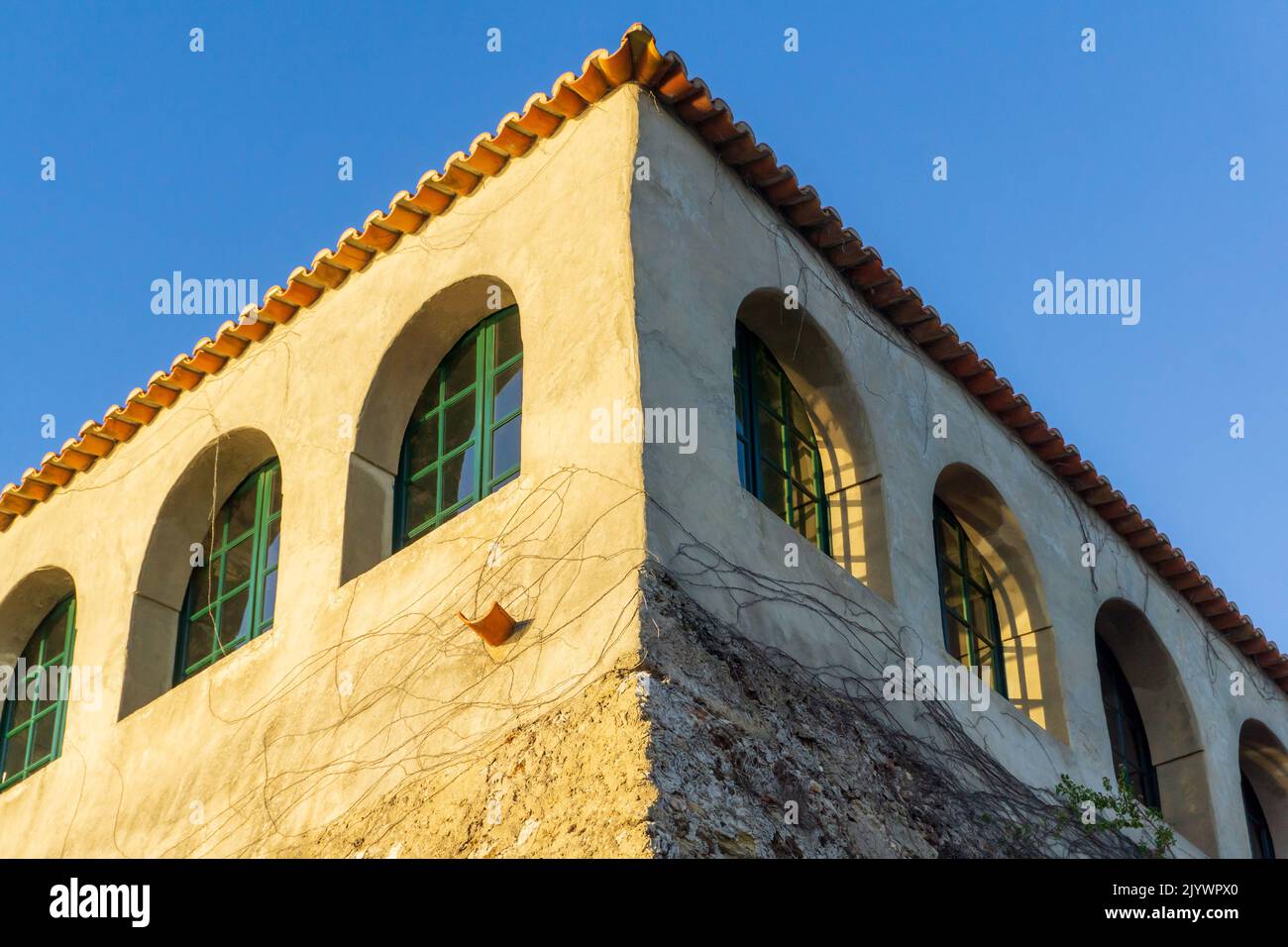 Building corner with green arched windows and tiled roof at sunset ...