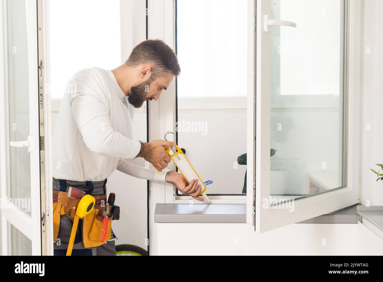 handsome young man installing bay window in a new house construction ...