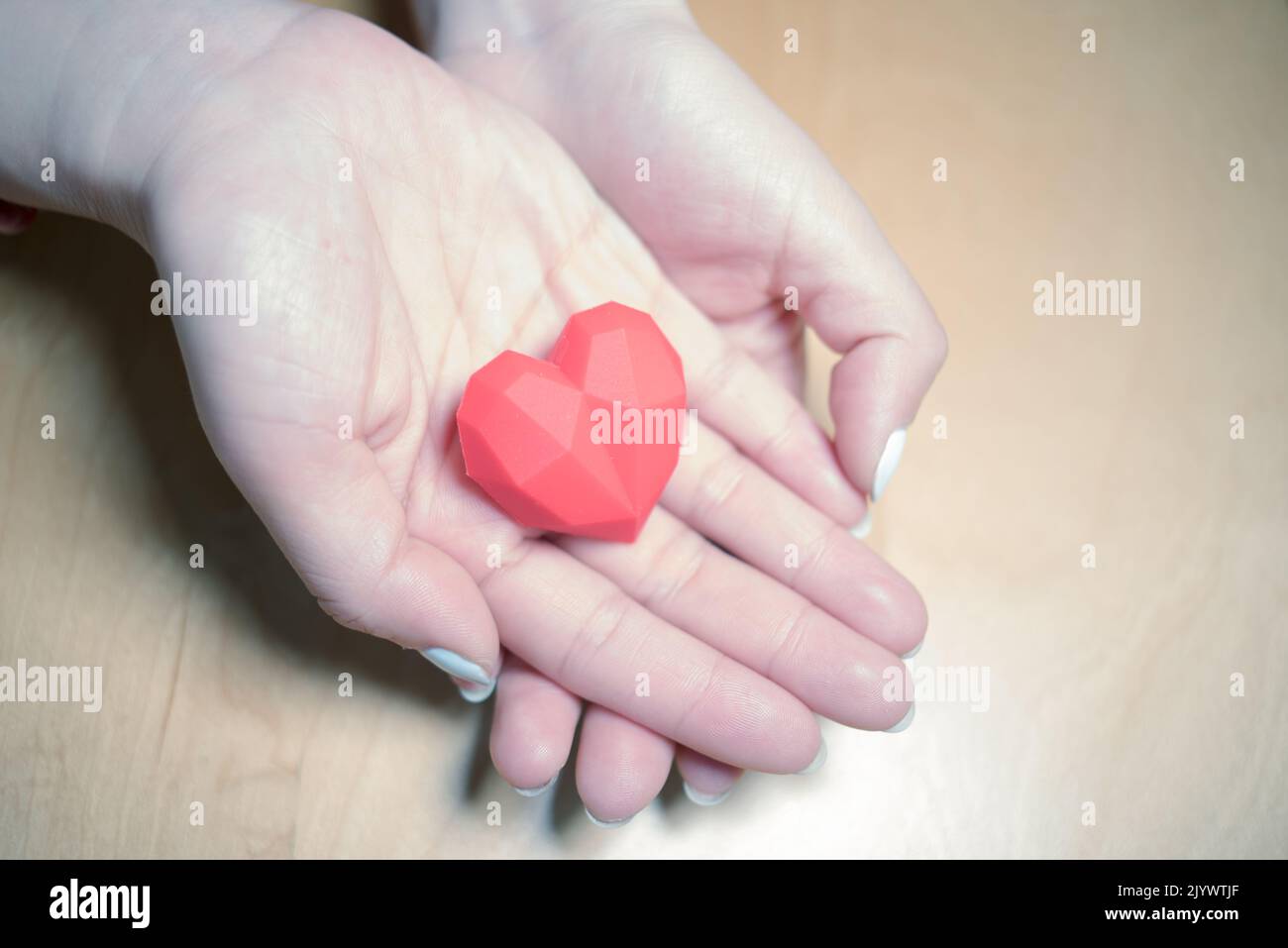 Adult holding red heart in hands over a wooden table. Family ... Adult holding red heart in hands over a wooden table. Family ...