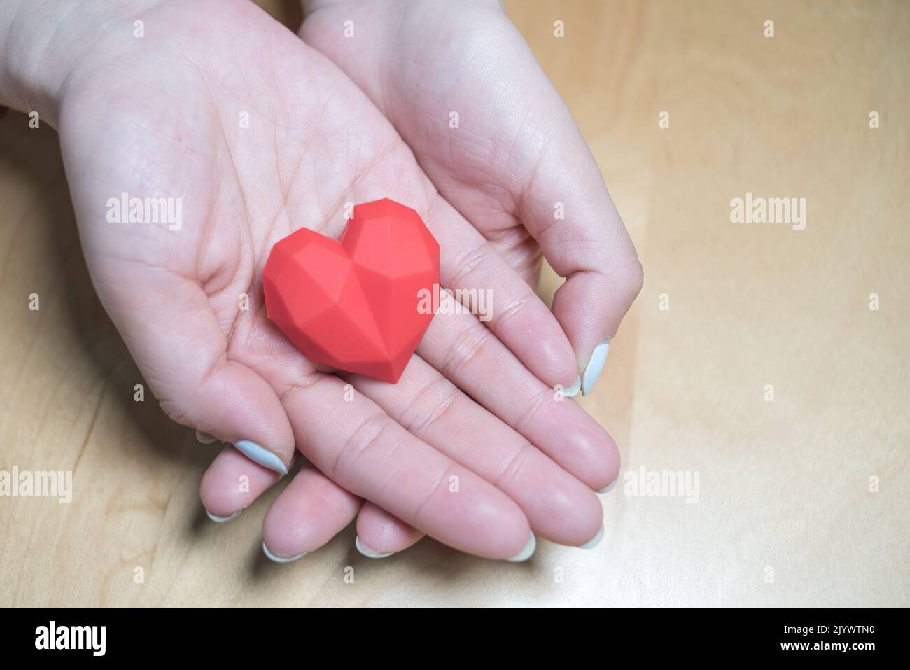 Adult holding red heart in hands over a wooden table. Family ... Adult holding red heart in hands over a wooden table. Family ...