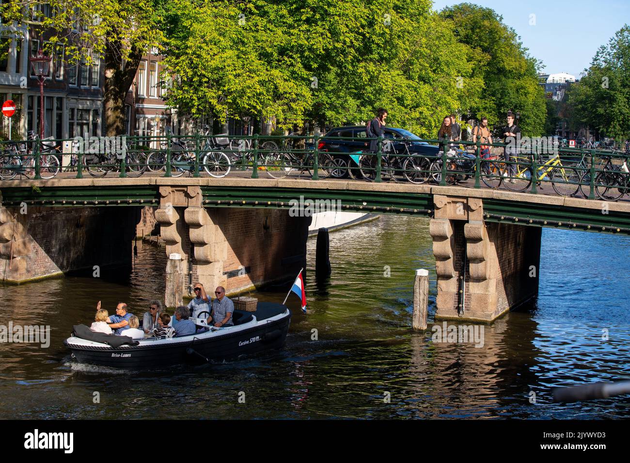 A boat having a sightseing tour crossing under an Amsterdam's bridge ...