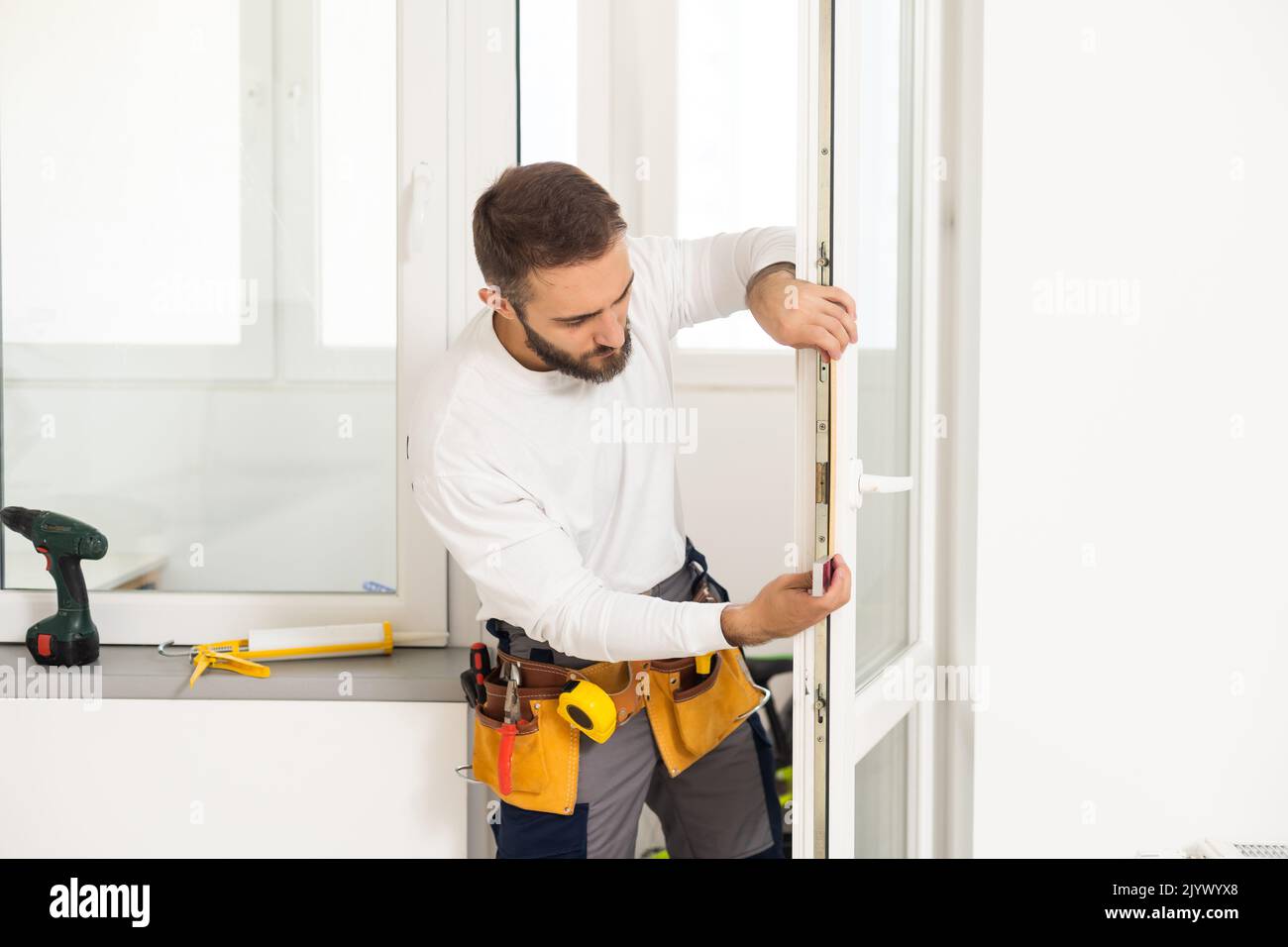 service man installing window with screwdriver Stock Photo - Alamy