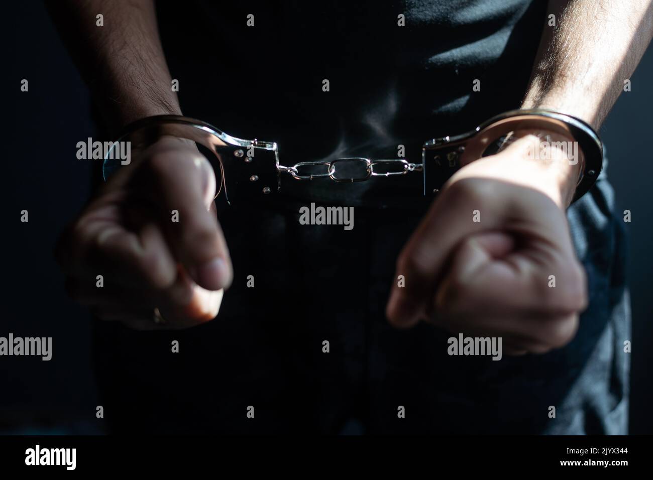 male hands in handcuffs black background Stock Photo - Alamy