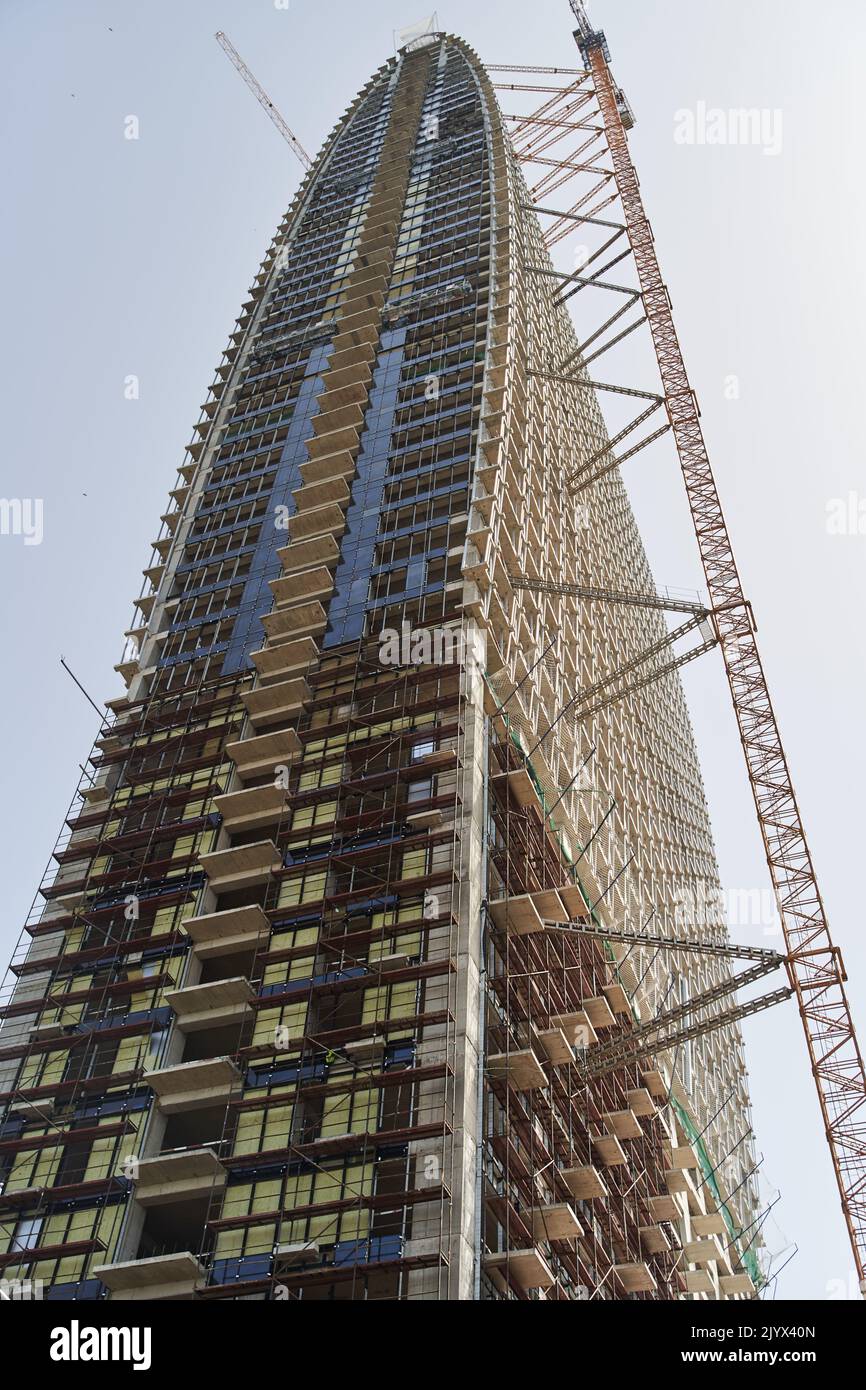 Bottom view of a high-rise building under construction with a crane ...