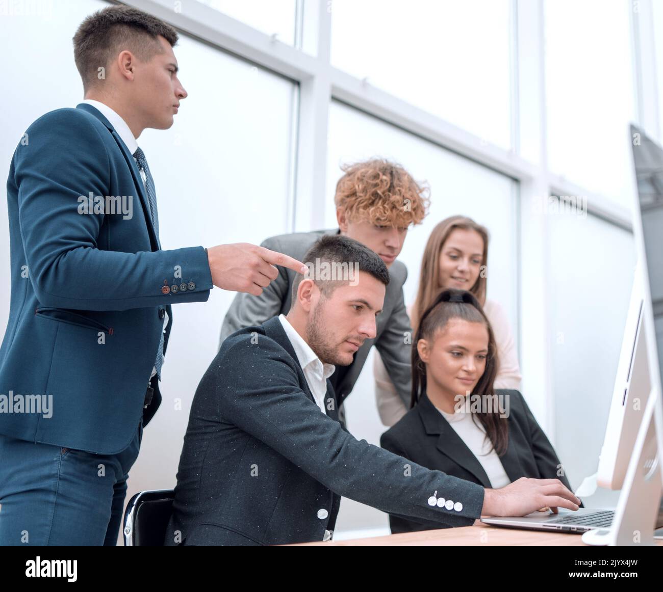 group of employees reading information on a computer screen Stock Photo ...