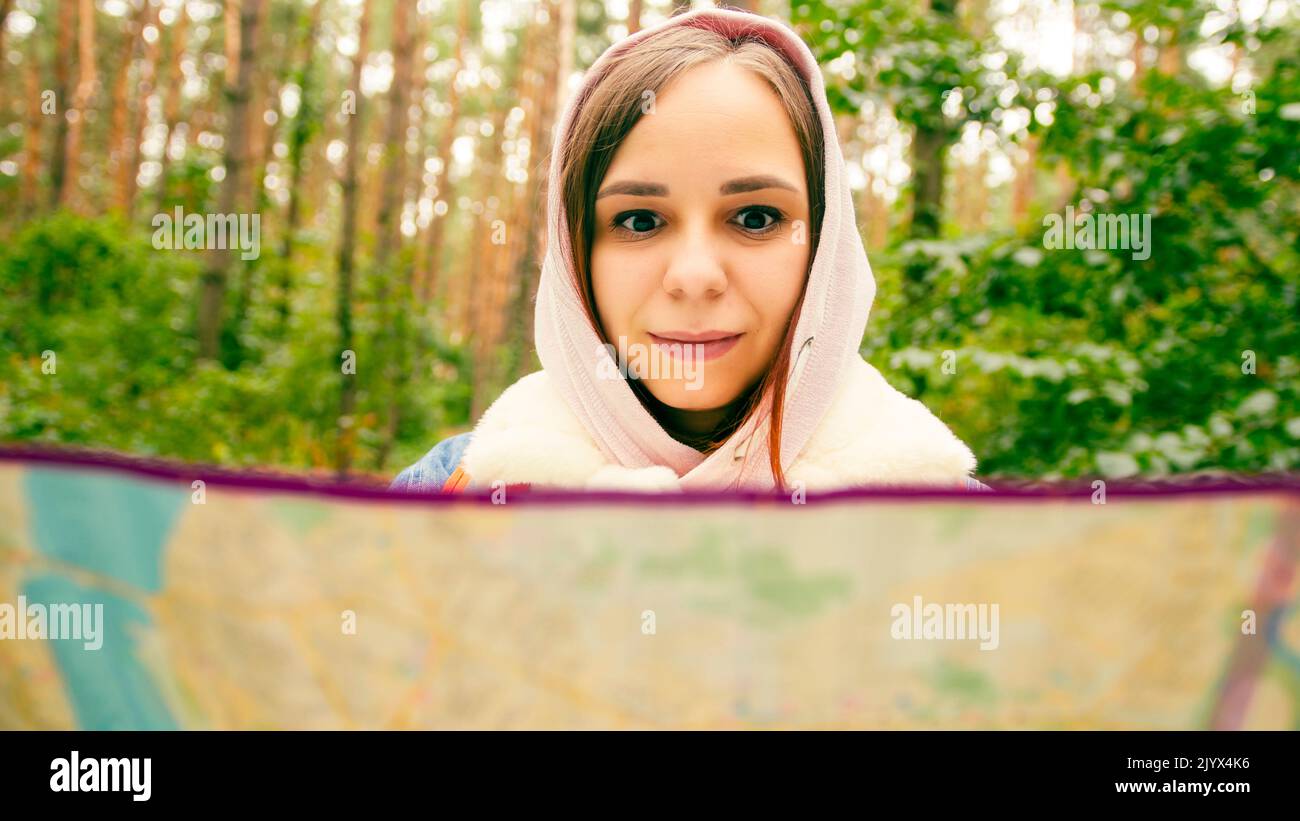 Cute girl reading map in forest. Traveling woman with backpack with ...