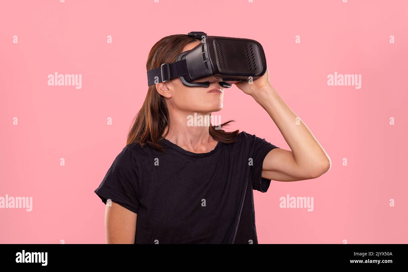Woman wearing a virtual reality headset, pink background Stock Photo ...