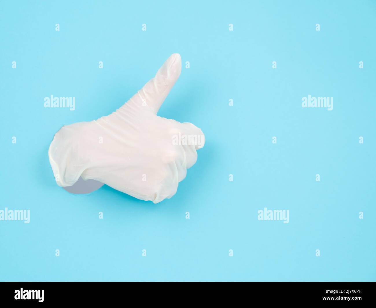 A female gloved hand sticks out through a blue paper background and ...