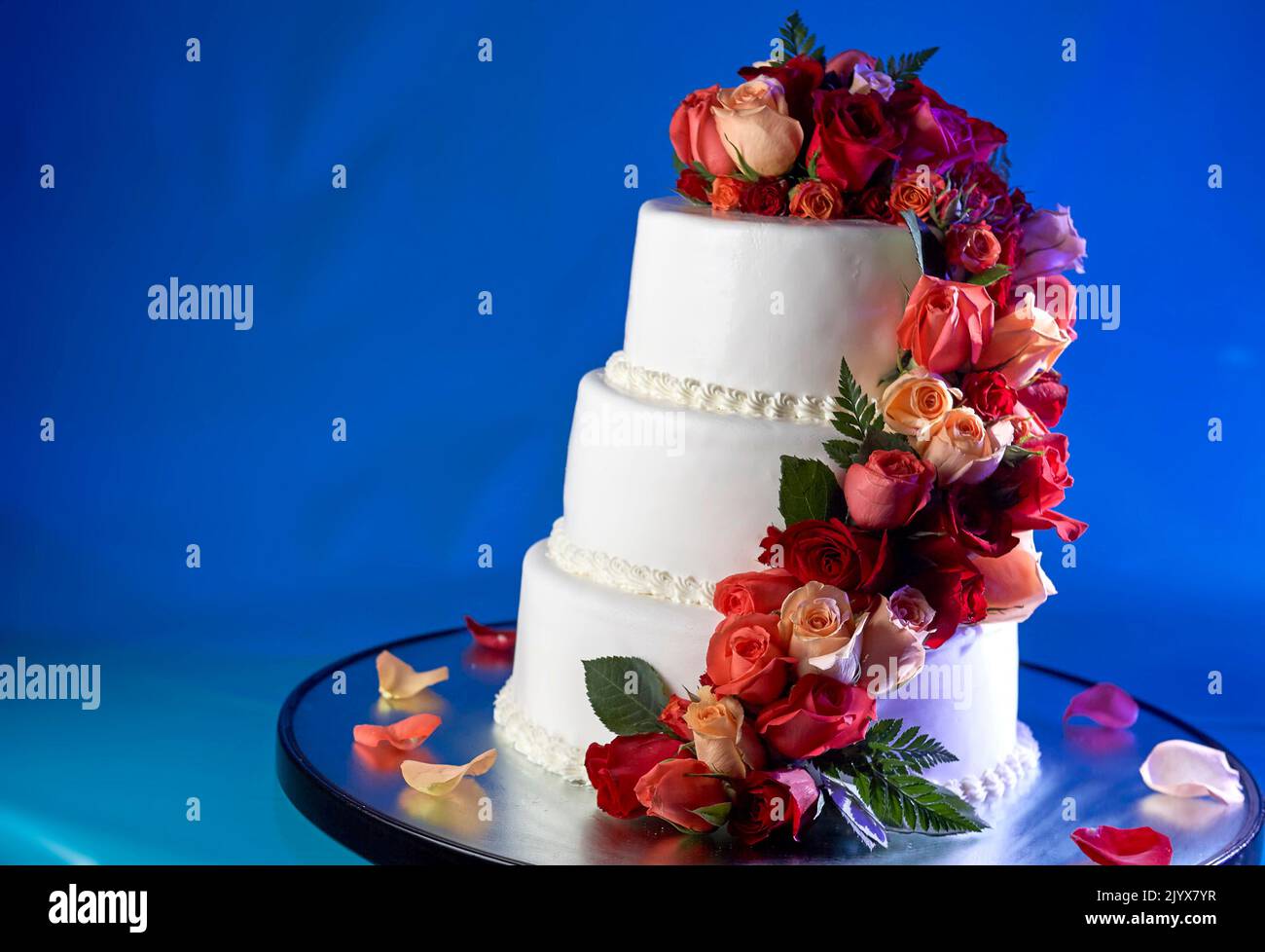 Wedding cake decorated with real roses. Cascading red and pink roses on ...