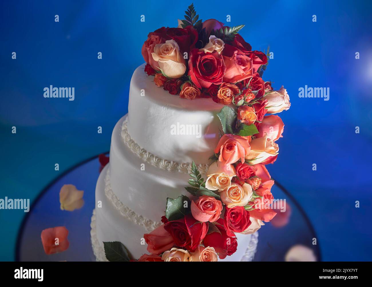 Wedding cake decorated with real roses. Cascading red and pink roses on ...
