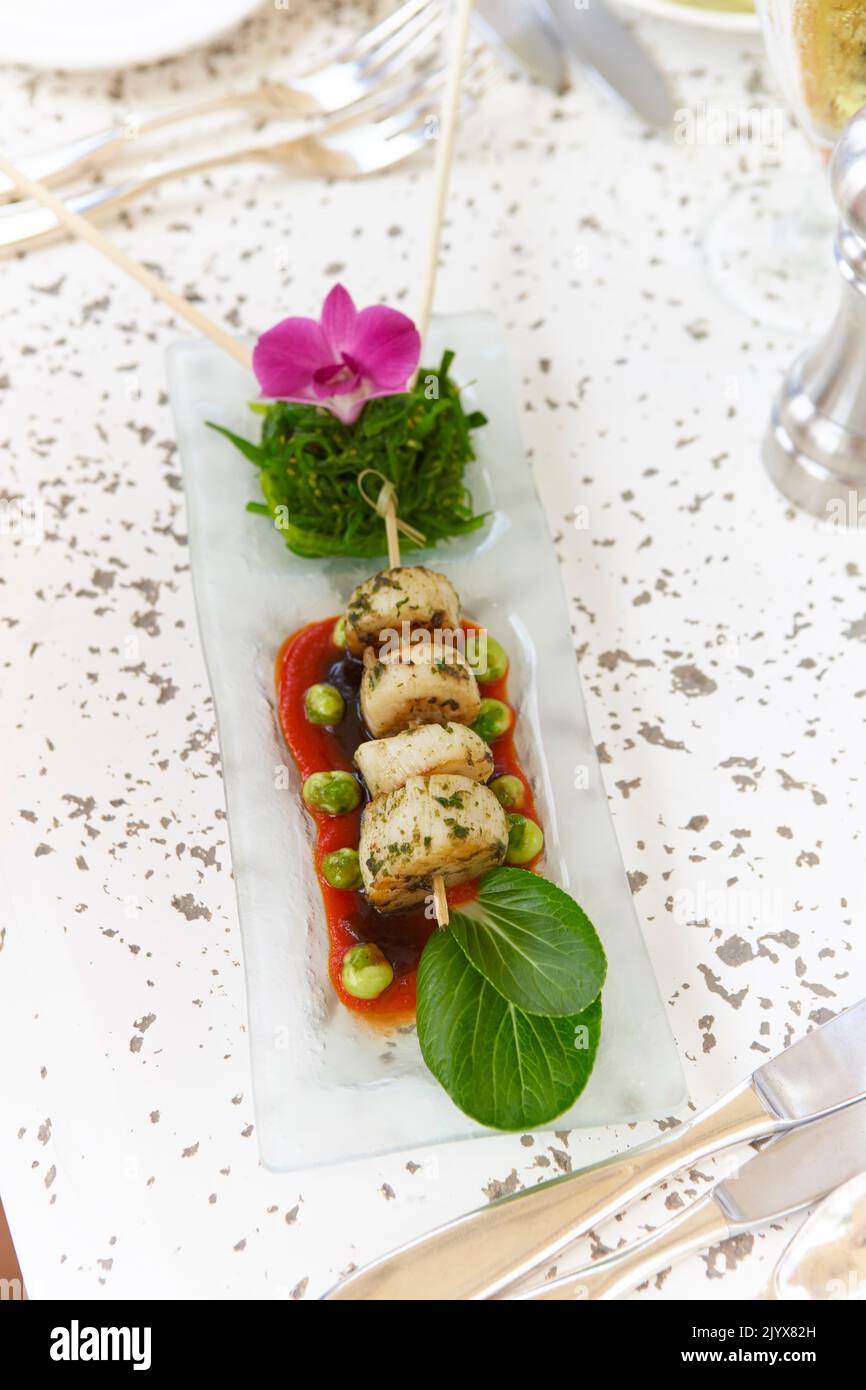 Gourmet cooked scallop dish with seaweed salad and baby bok choi park ...