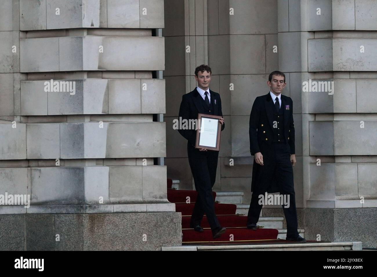 A member of royal household staff posts a notice on the gates of the ...