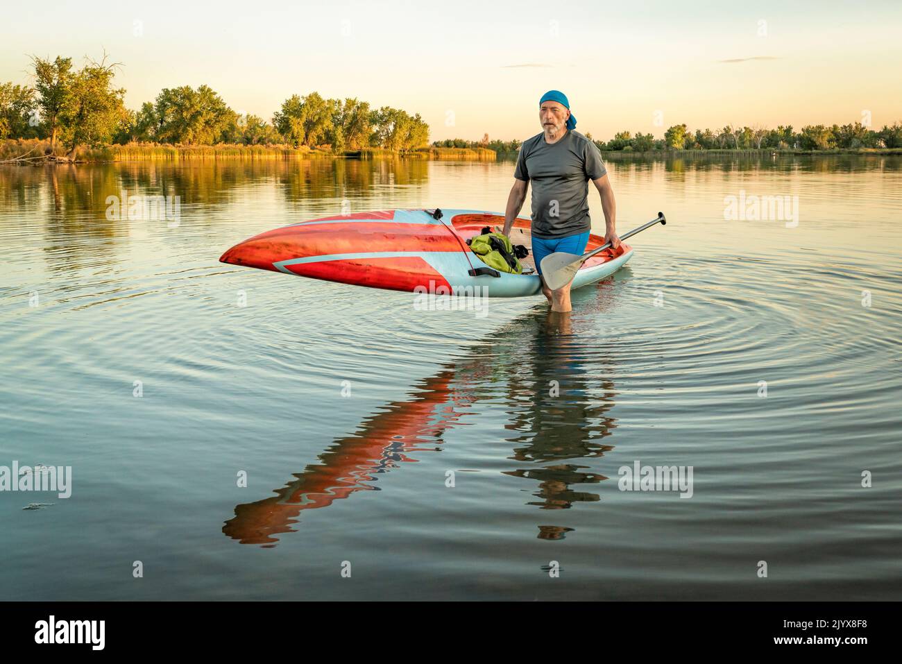 senior male paddler with a long and narrow racing stand up paddleboard ...