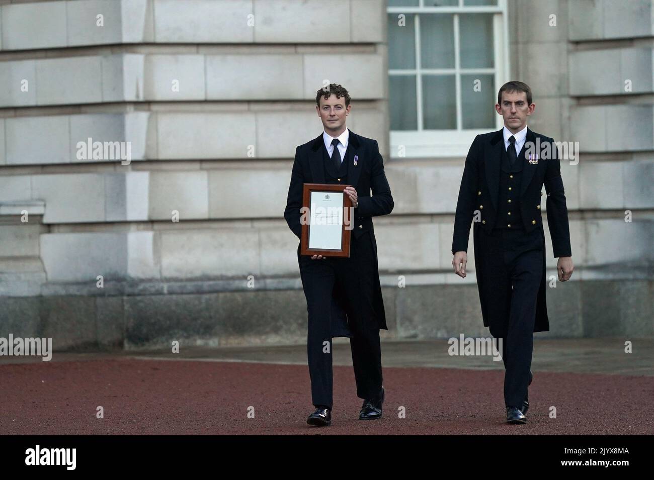 A member of royal household staff posts a notice on the gates of the ...