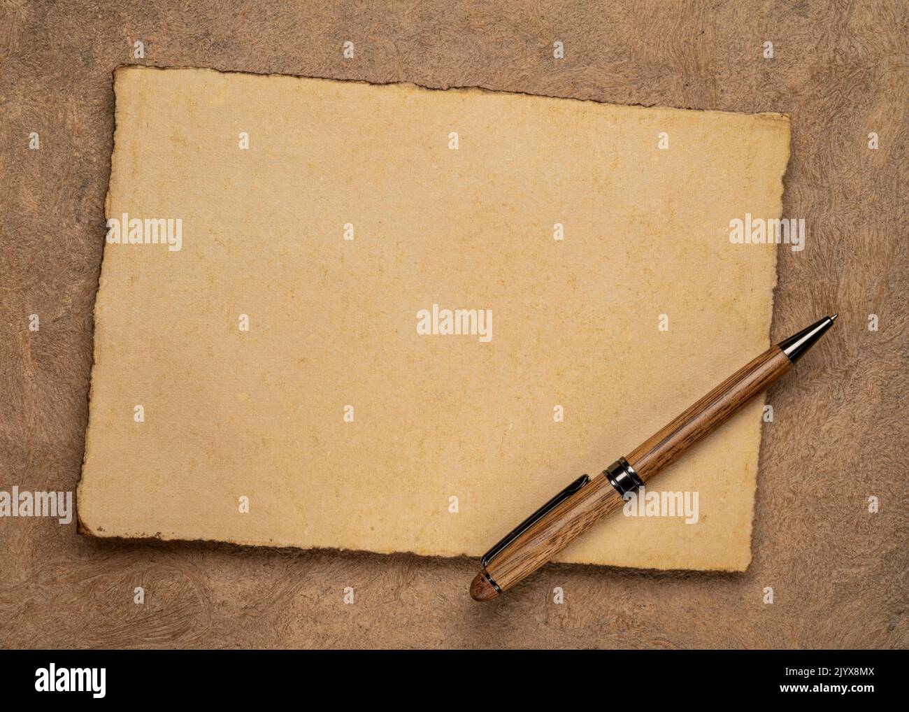 sheets of blank handmade paper with rough edges and a stylish pen ...