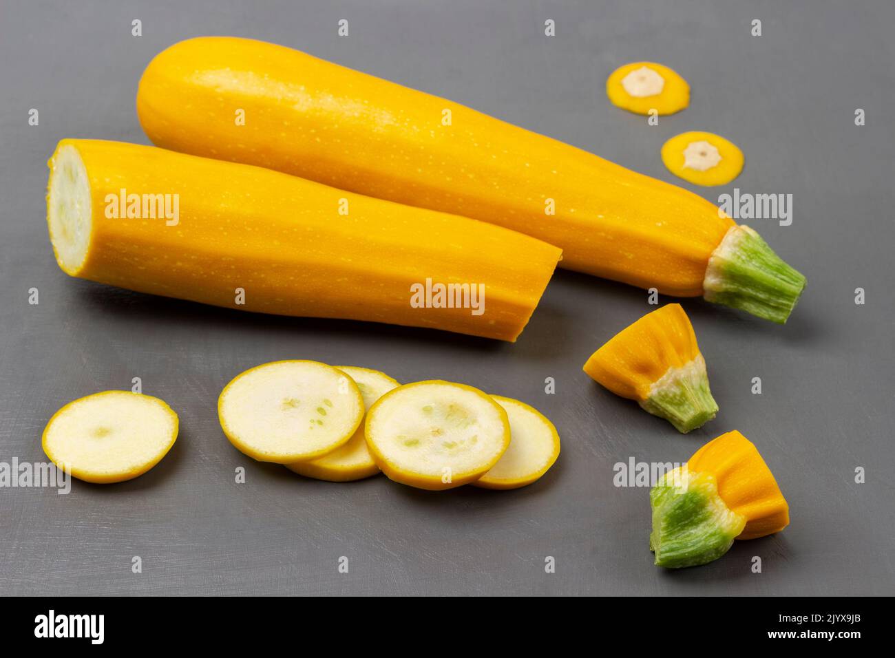 Whole zucchini and sliced yellow zucchini. Top view. Grey background ...