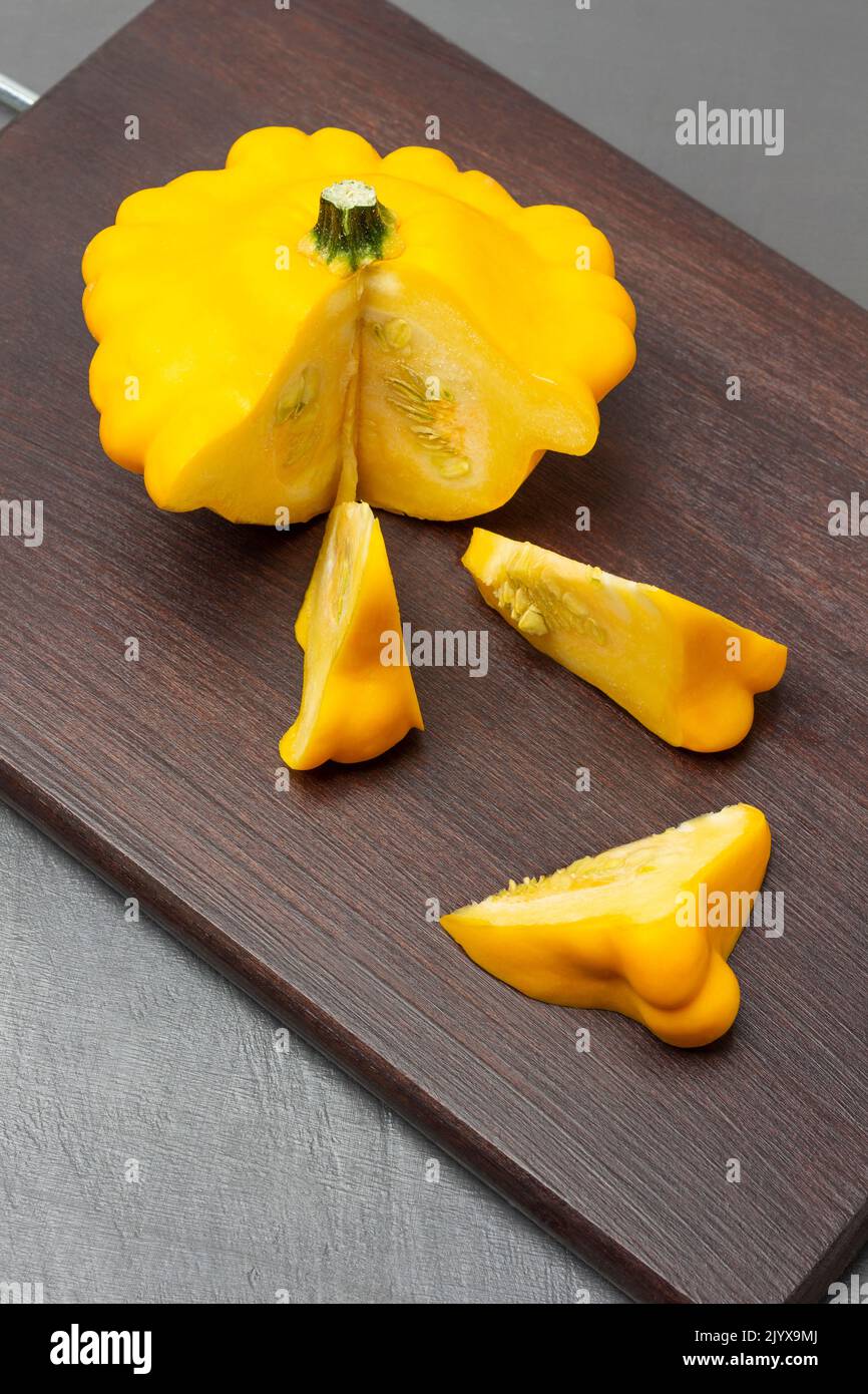 Sliced pieces of yellow patisson on cutting board. Top view. Grey ...