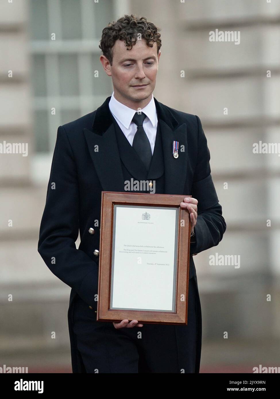 A member of royal household staff posts a notice on the gates of the ...