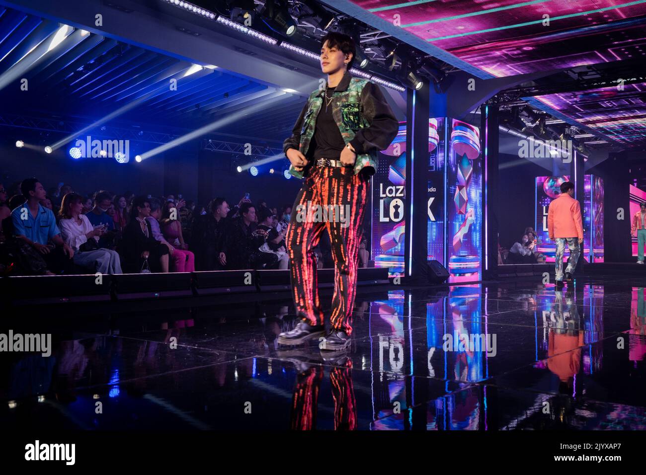 Models are seen walking around popular Thai band LAZ1 as they perform ...