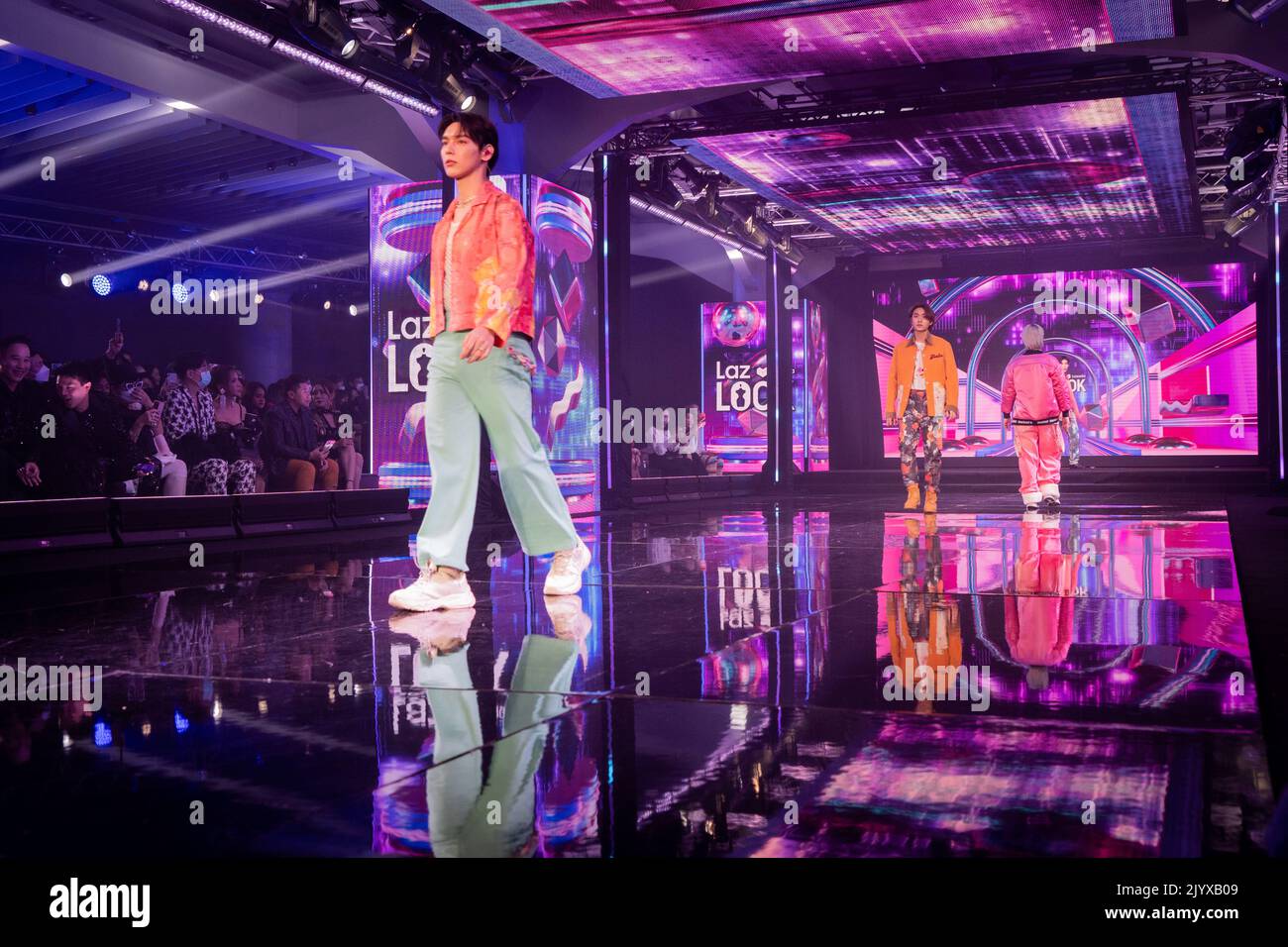 Models are seen walking around popular Thai band LAZ1 as they perform ...
