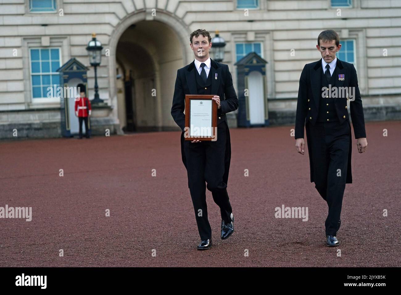 A member of royal household staff posts a notice on the gates of the ...