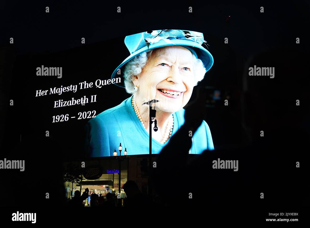 A tribute to Queen Elizabeth II is displayed on a big screen in ...