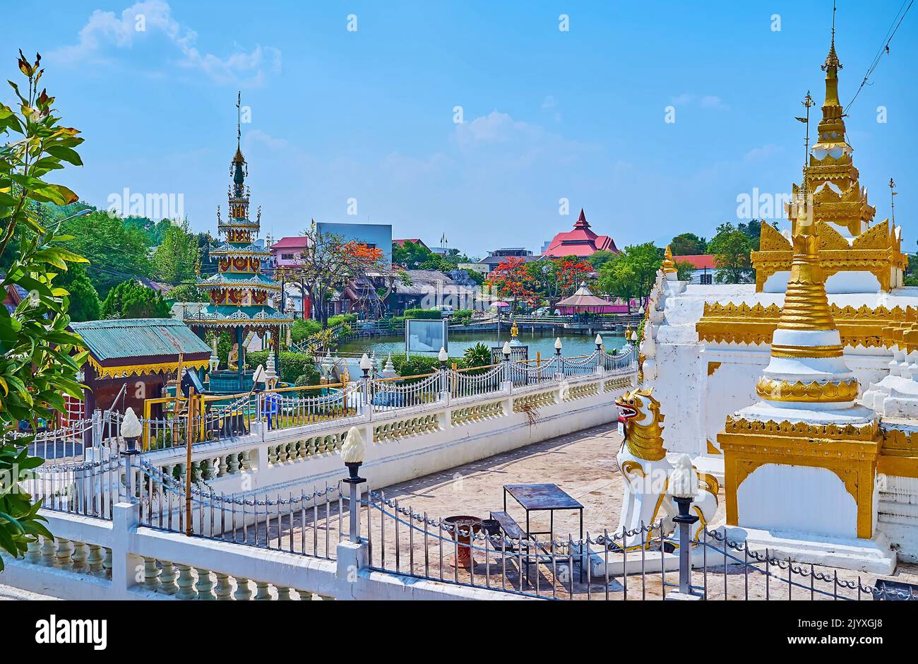 The statue of Chinthe (Singha) lion at the carved white-golden Chedi of ...