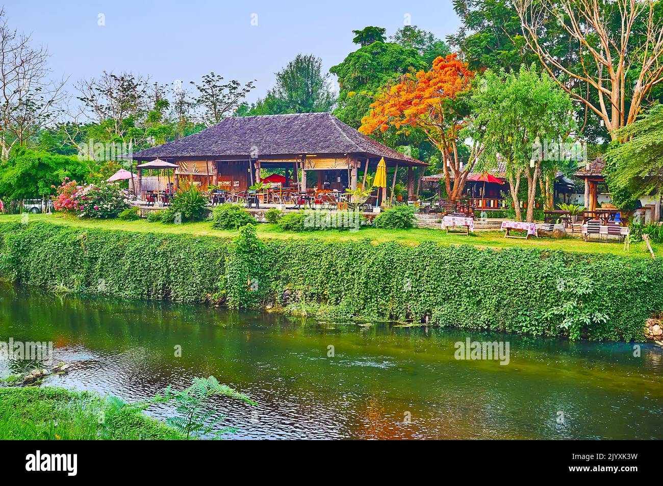 The old wooden pavilion of the restaurant with lush green garden and ...