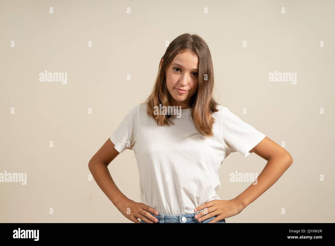 Cute spanish girl with brunette hair looking at camera with arms akimbo ...