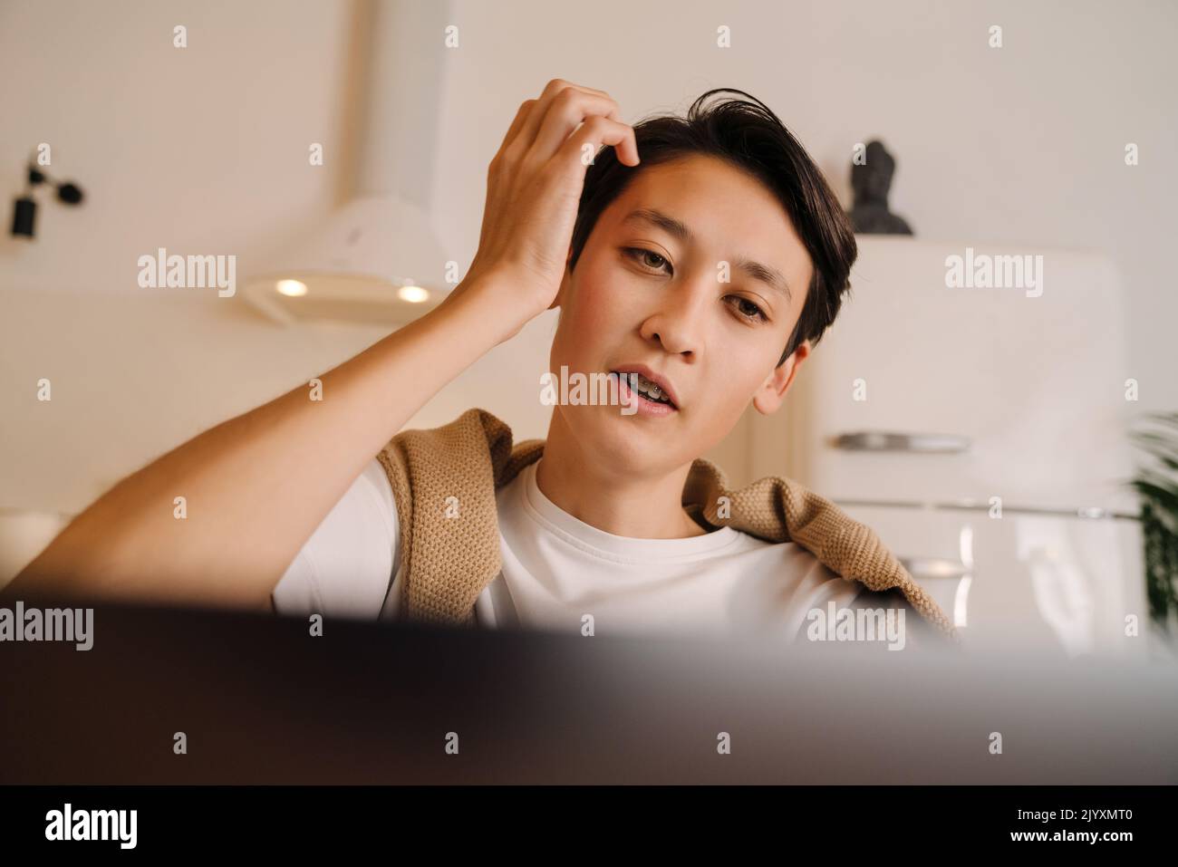 Asian boy working with laptop while sitting in kitchen at home Stock ...