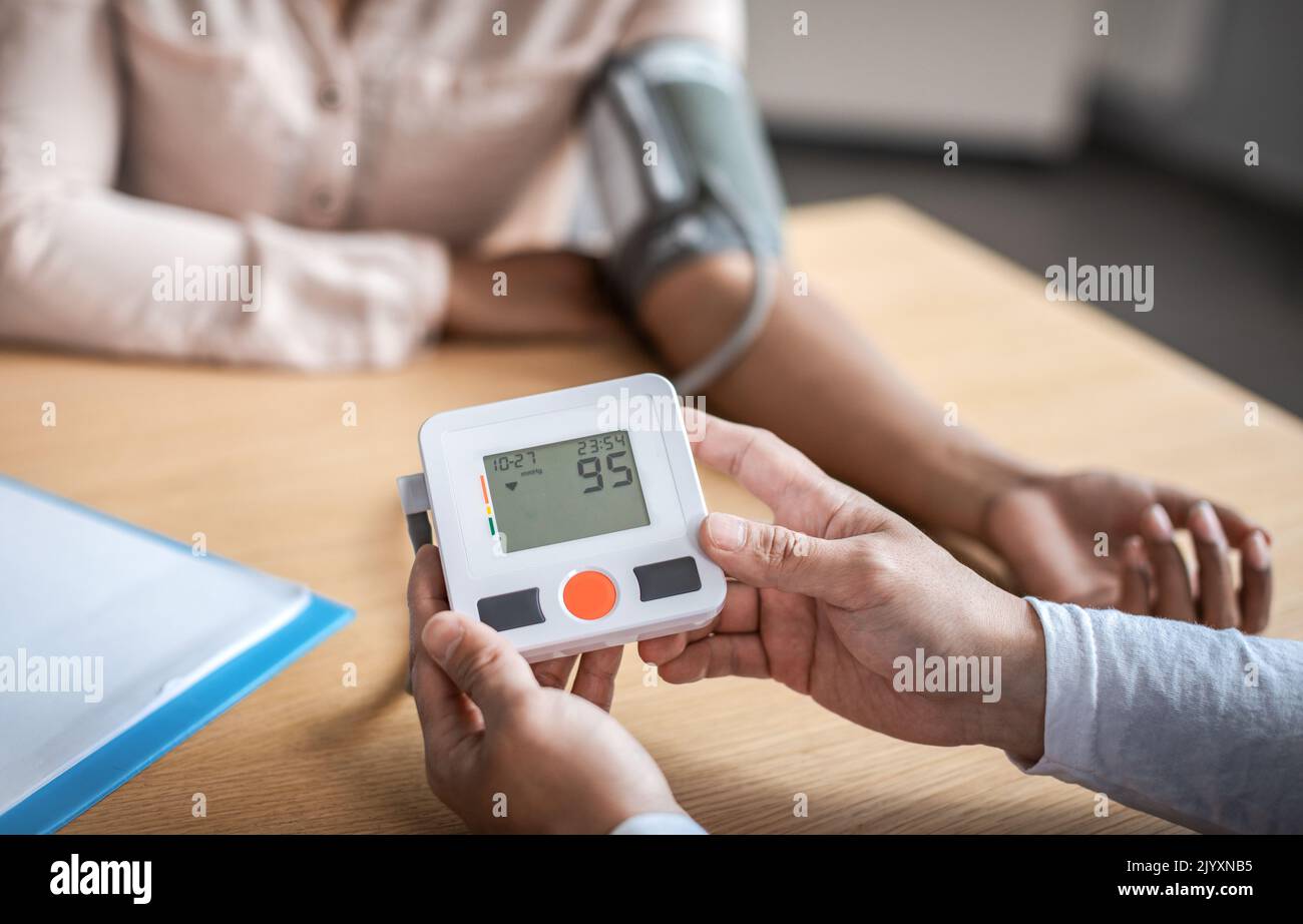 Asian man measures pressure to young black lady patient and shows ...