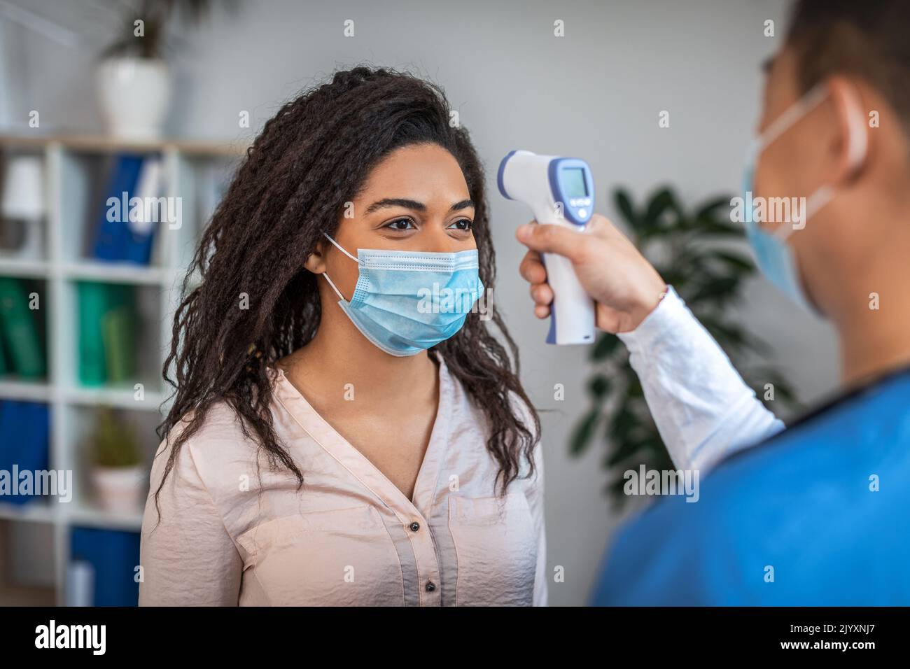 Millennial asian man checks temperature with thermometer of young black ...