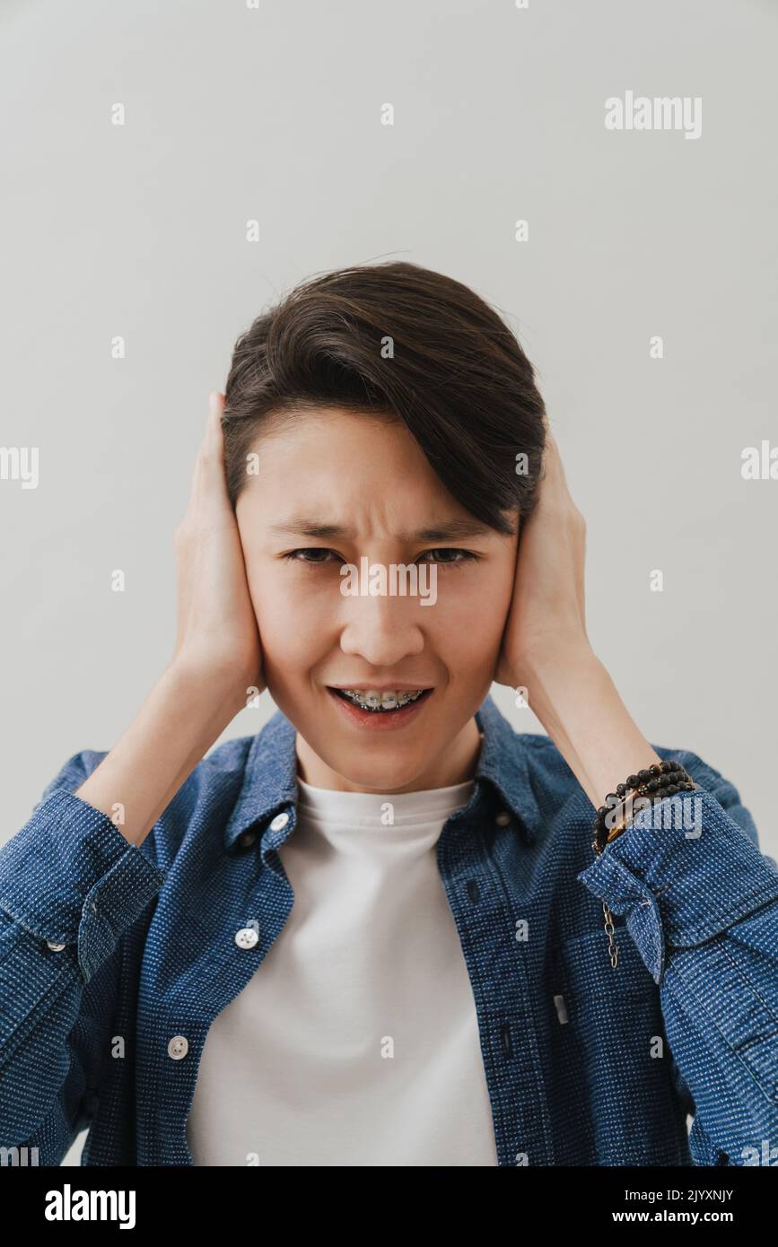Asian boy wearing shirt covering his ears while posing on camera ...