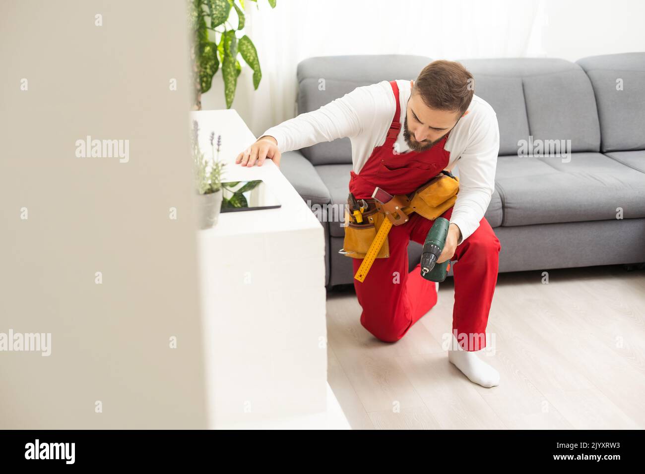 Professional technician sealing electric fireplace near white wall in ...