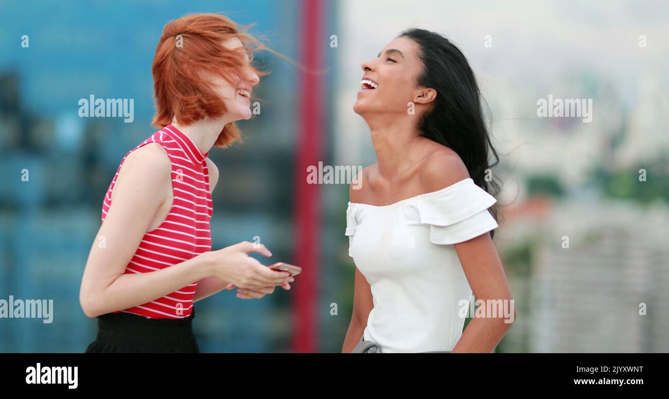 Two young women looking cellphone screen burst out laughing. Real life ...