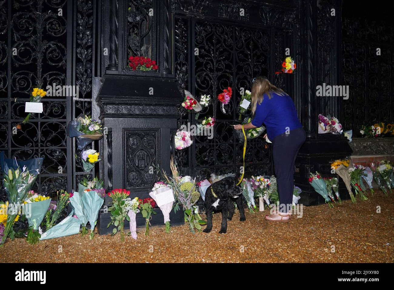A woman lays flowers with her dog Dexter at the gate of Sandringham ...