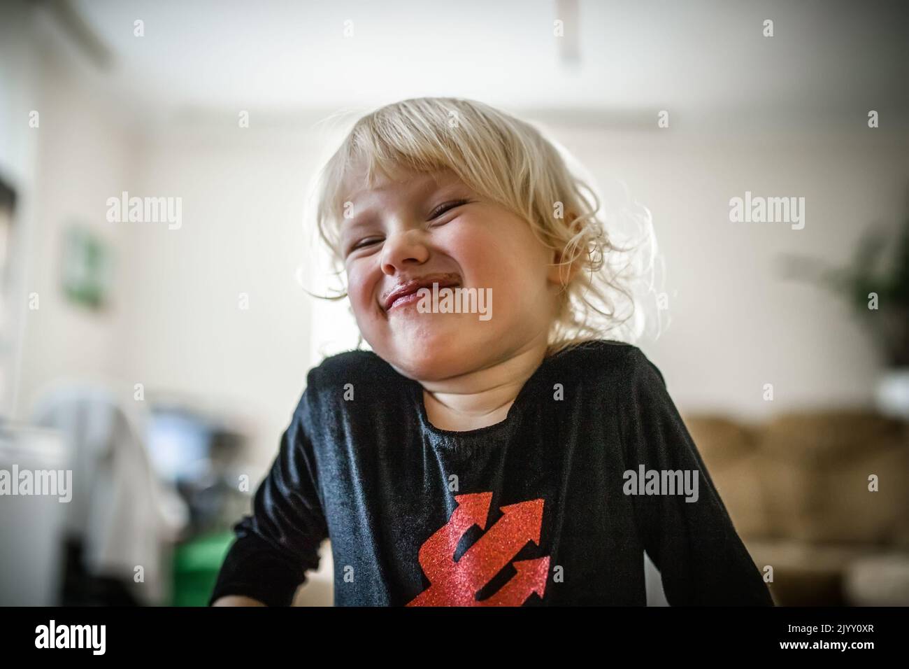 A funny girl writhes a face against the background of a room in a ...