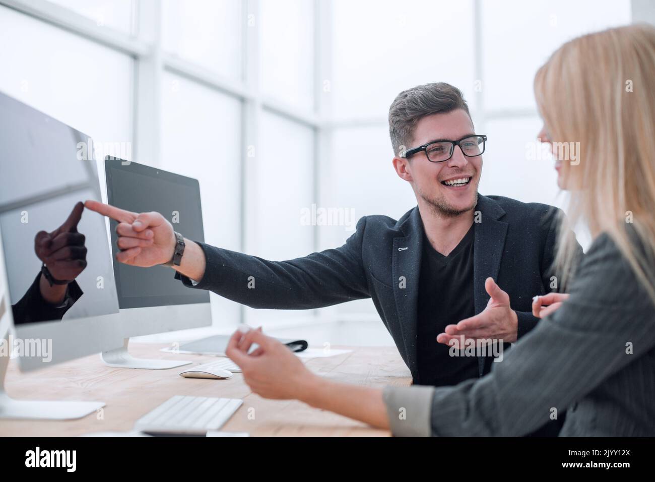 two business colleagues discussing a work project at the desktop Stock ...