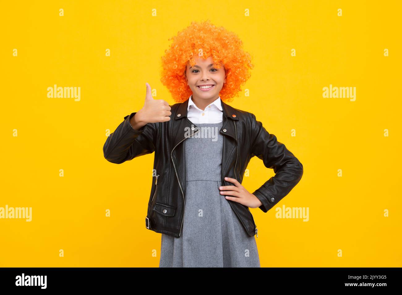 Birthday kids party. Funny kid in curly clown wig isolated on yellow ...